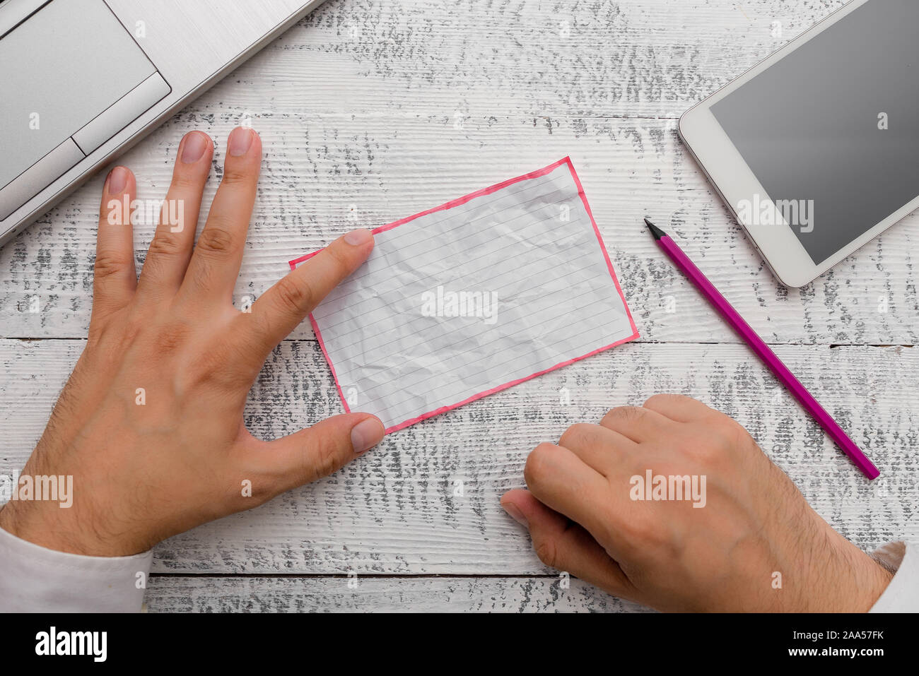 Hand hold note paper near writing equipment and modern smartphone ...