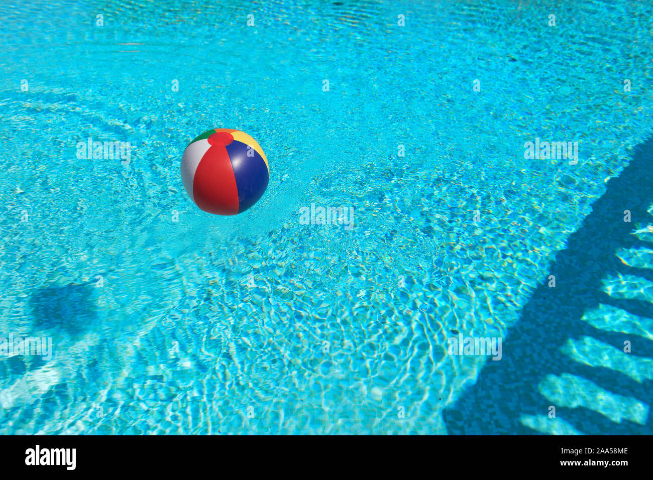 Inflatable colorful beach ball floating in water from swimming pool ...