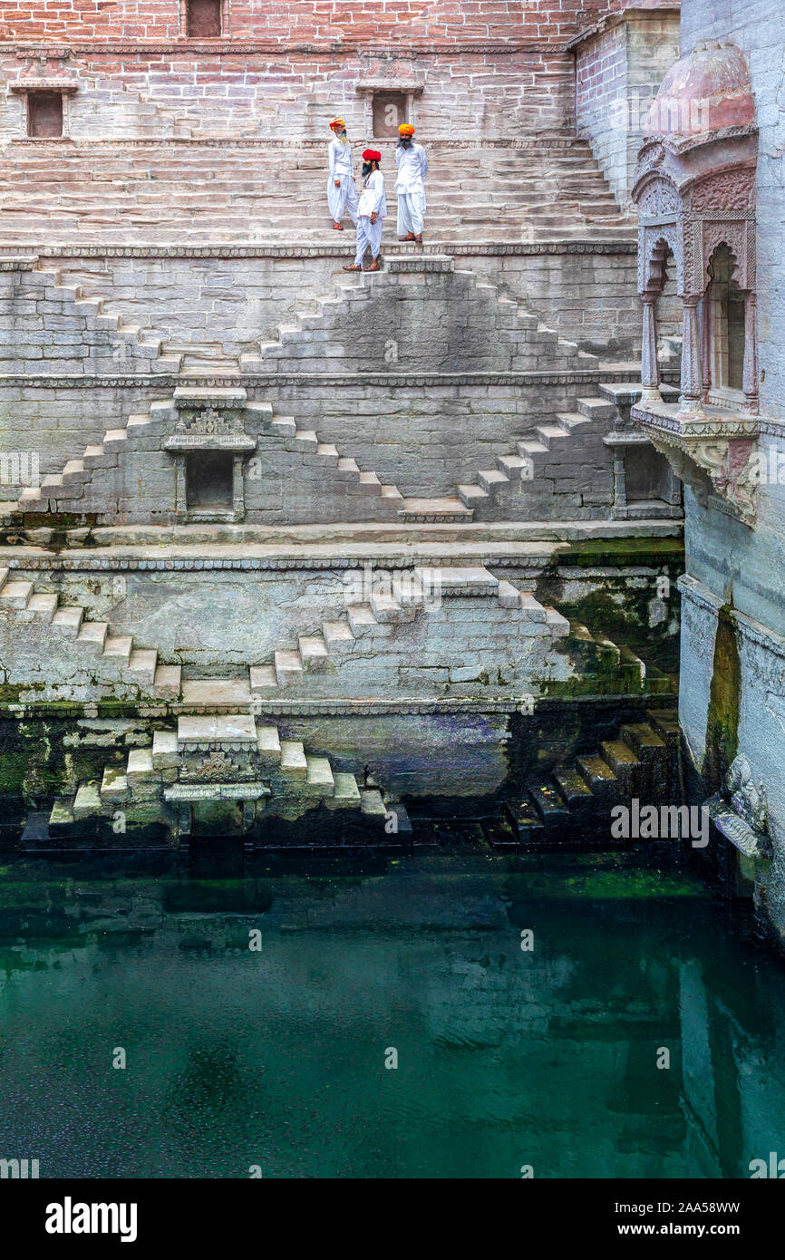 Three men walking down the steps at the stepwell Toorji Ka Jhalra in ...