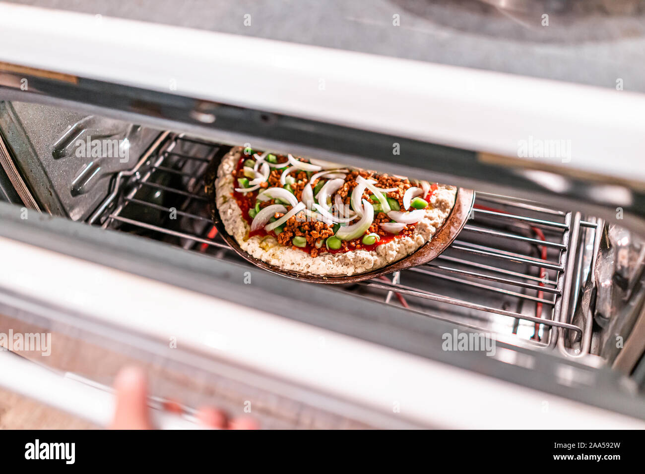 Hand opening oven door for homemade pizza cooking baking with tomato ...