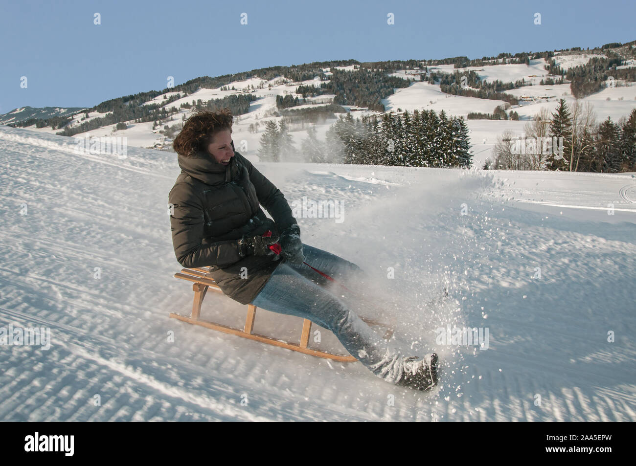 Young woman riding sled in the Bavarian alps Stock Photo - Alamy