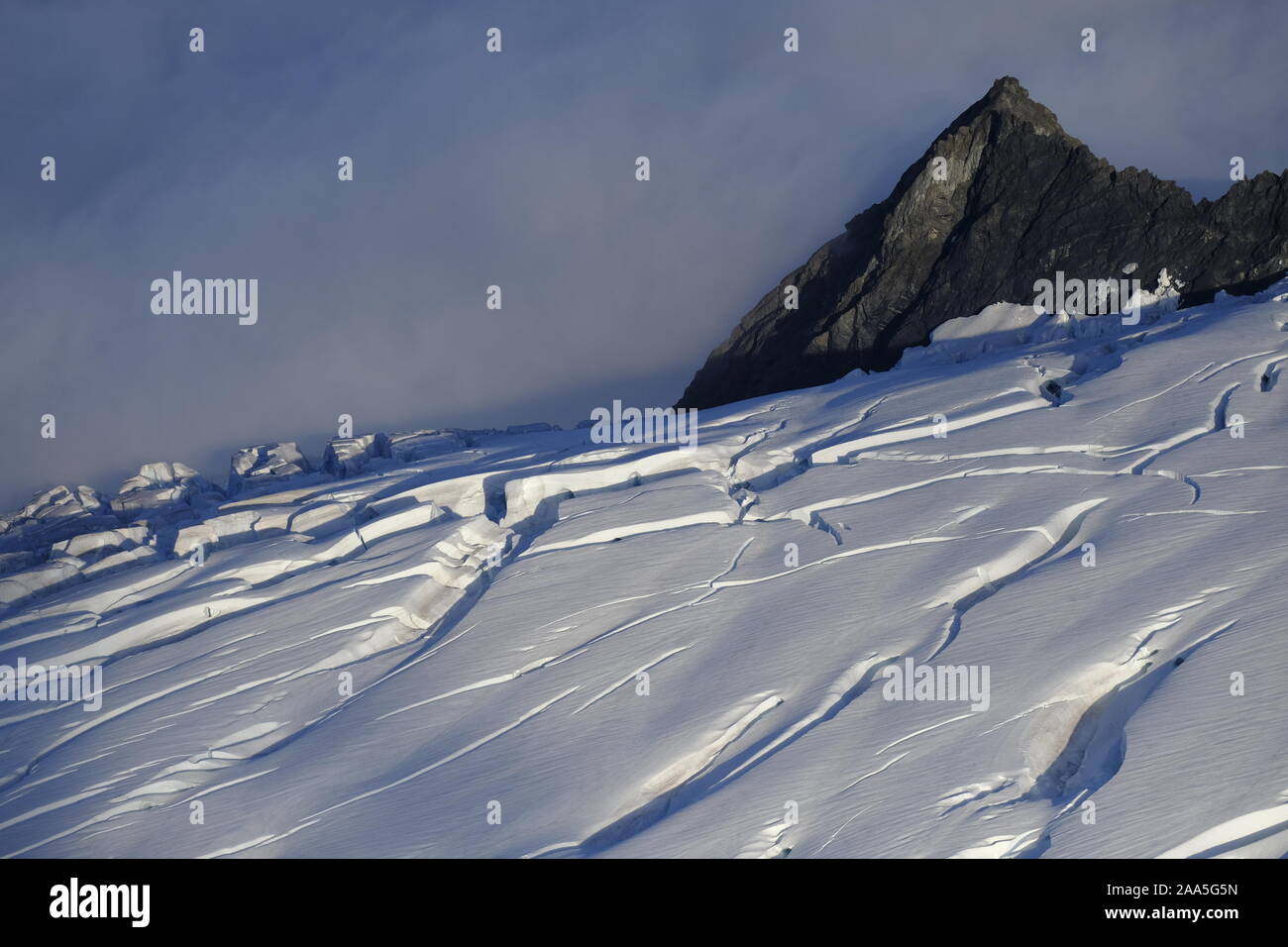 Aerial photo of a rocky spire and a crevasse filed glacial snowfield in ...