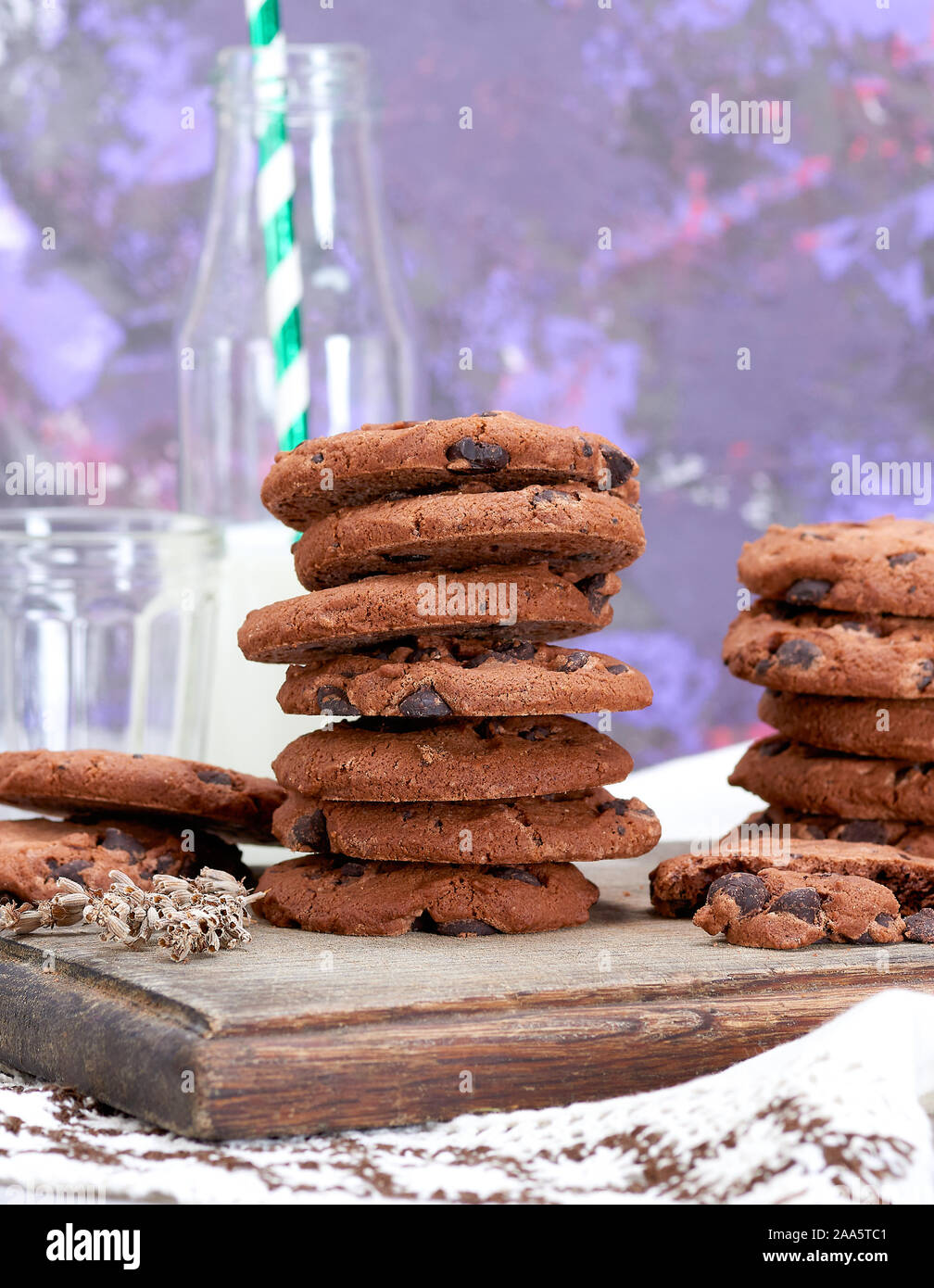 stack of round chocolate chip cookies on a brown wooden board, behind a ...