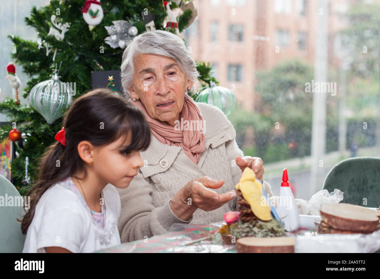 Grandmother teaching her granddaughter how to make christmas Nativity ...