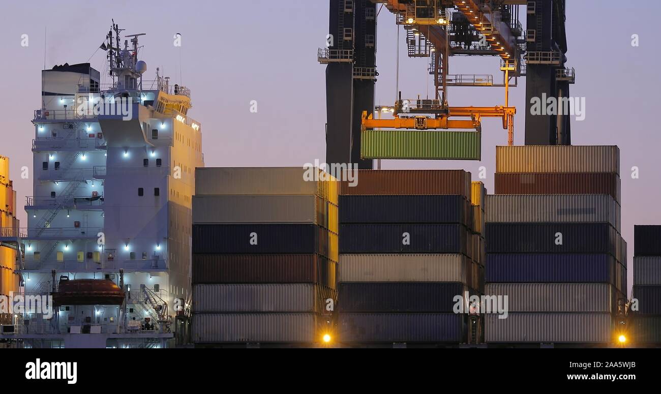 Loading containers on a ship at dawn Stock Photo - Alamy