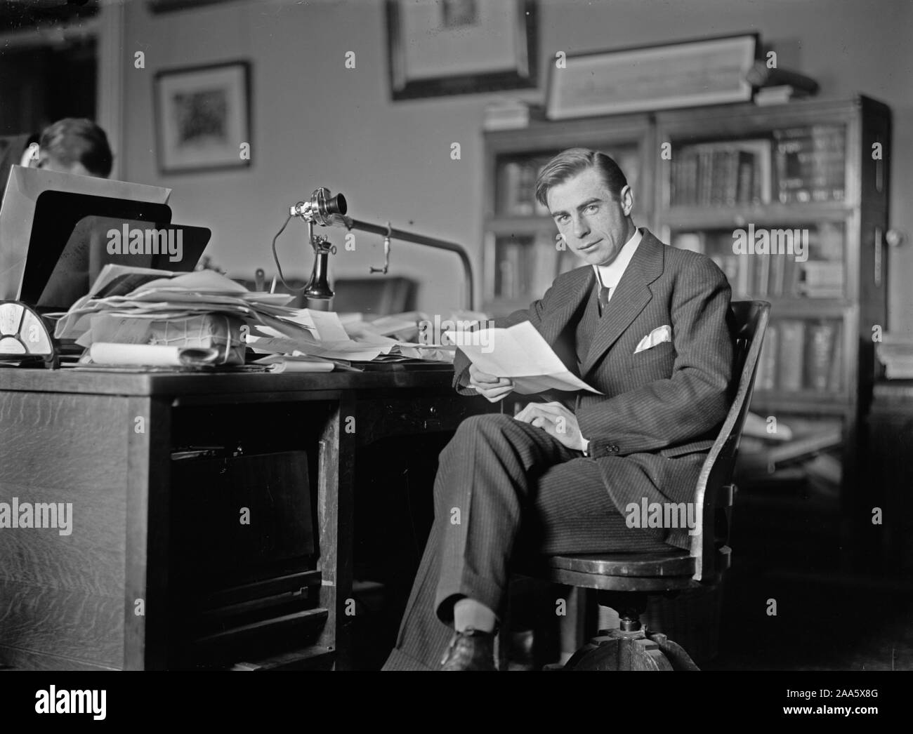 Man sitting at his office desk looking at a piece of paper ca. 1911 ...