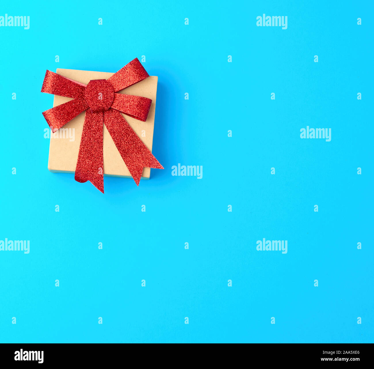 closed brown gift box with a red shiny bow on a blue background, top ...