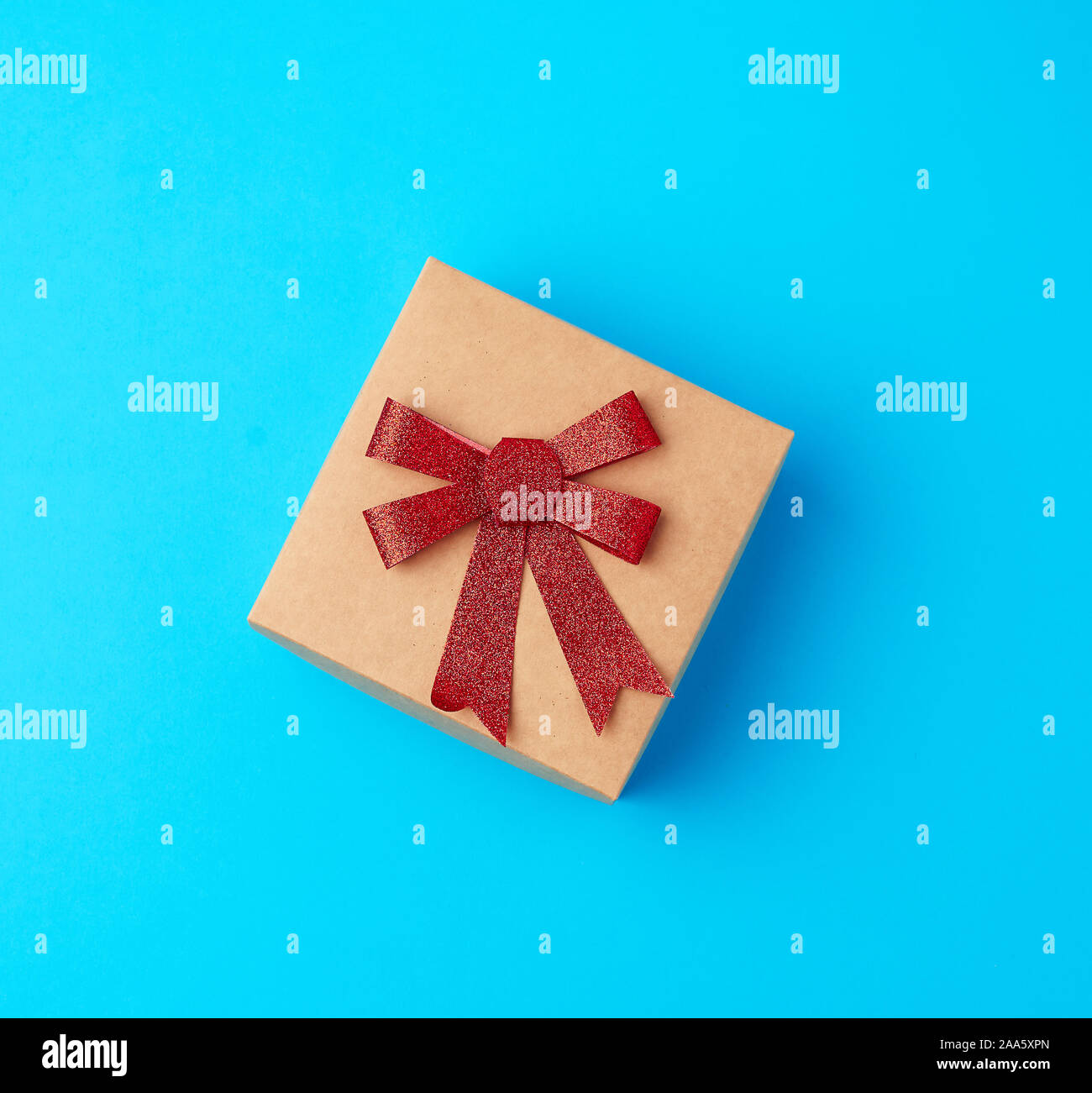 square gift box with a red bow on a blue background, top view, festive ...