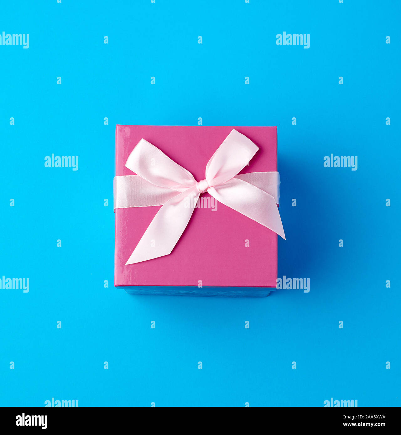closed pink cardboard box with a bow on a blue background, top view ...