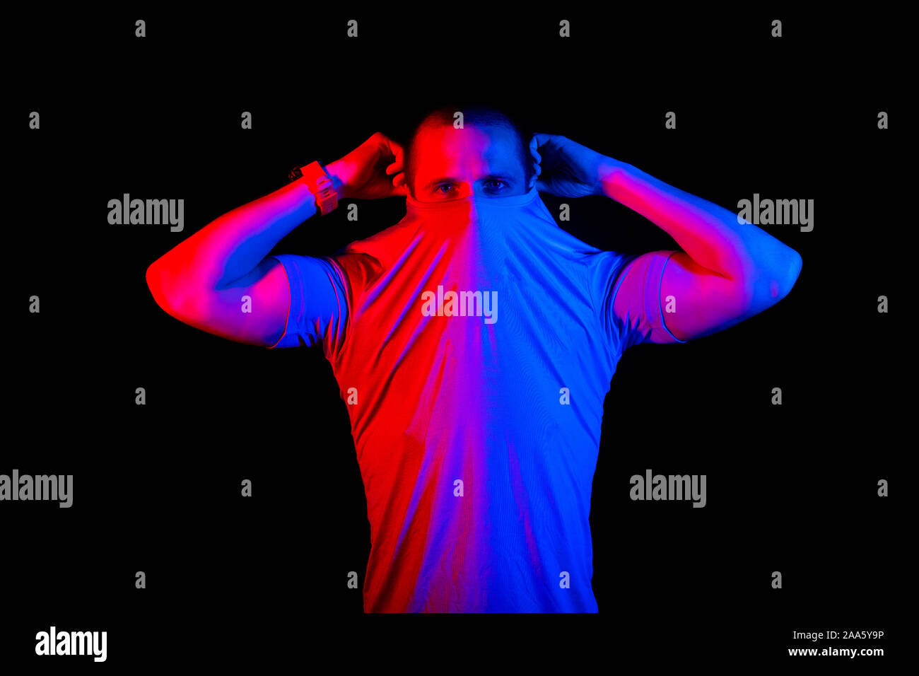 Man hiding his face under t-shirt, red and blue color light Stock Photo ...