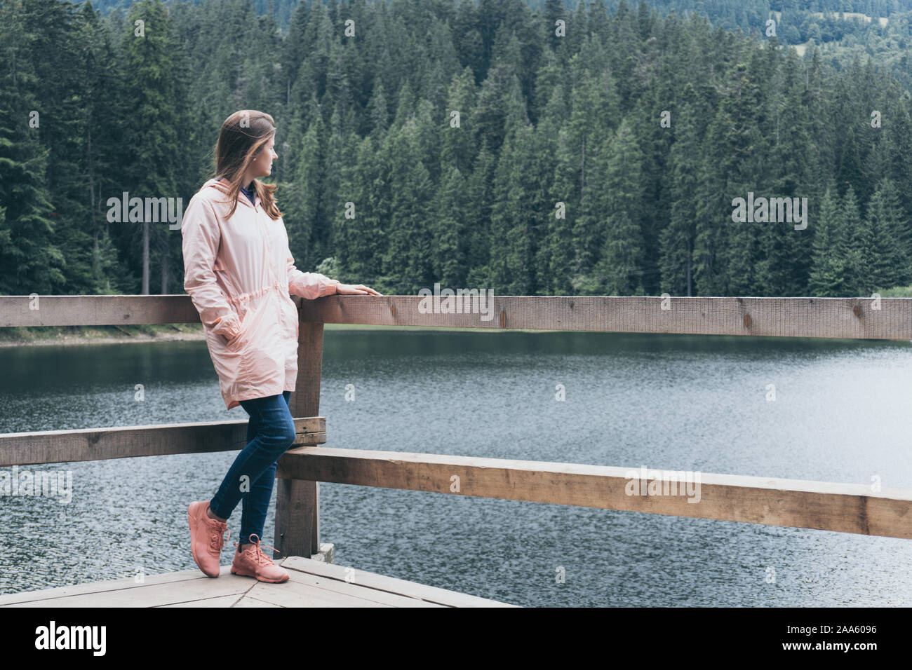 Woman standing in pier near mountain lake and forest Stock Photo - Alamy