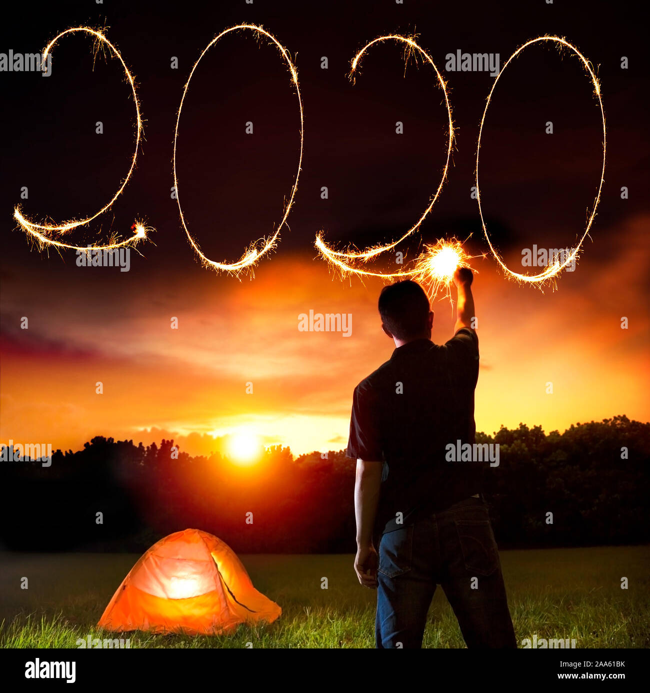 young man celebrating and drawing 2020 new year by sparkles Stock Photo ...