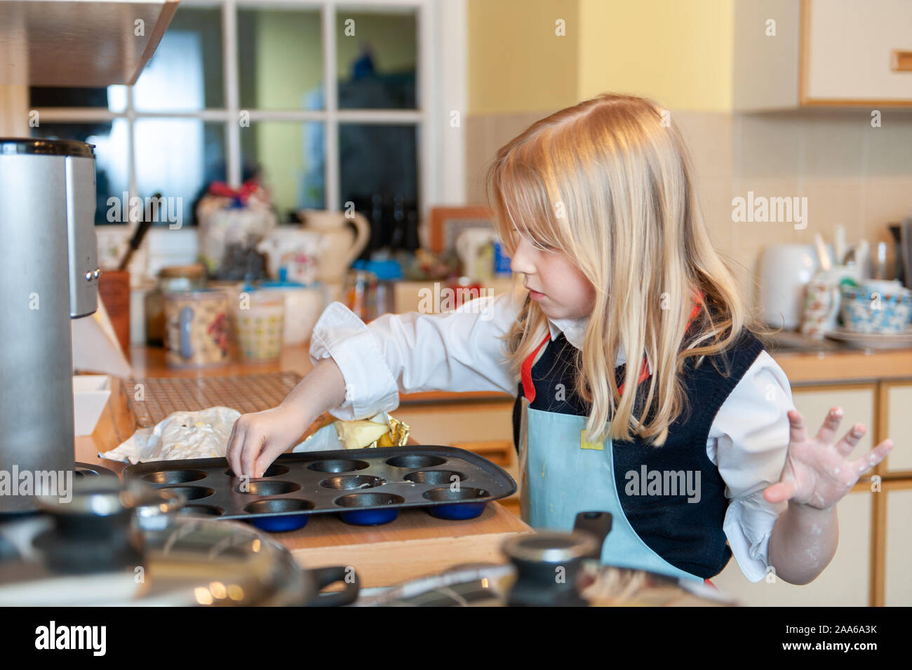 Pretty young blonde girl baking in a messy kitchen Stock Photo - Alamy