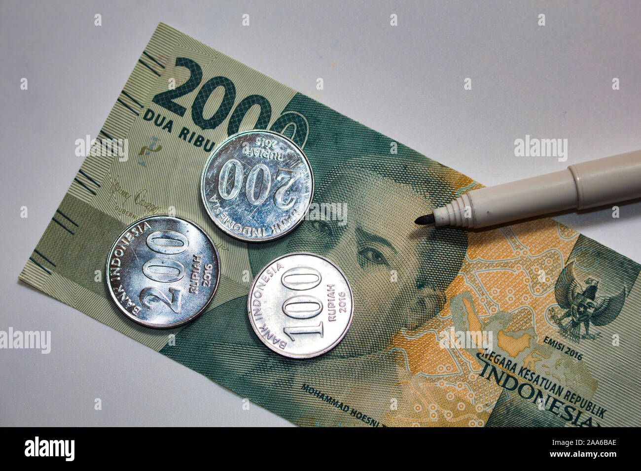 Indonesian rupiah currency, bill, coins, and pen with white background ...
