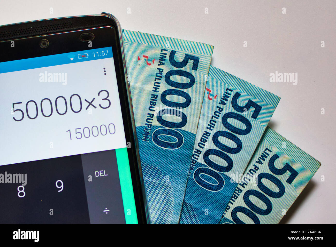 Indonesian rupiah bills and a mobile phone running a calculator ...