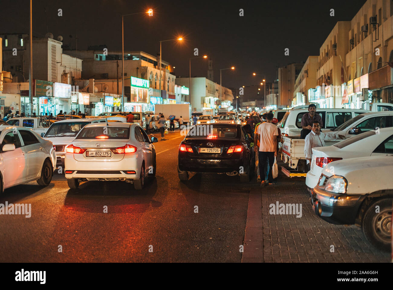 Traffic and parked cars in the street at night, in front of Souq Al ...