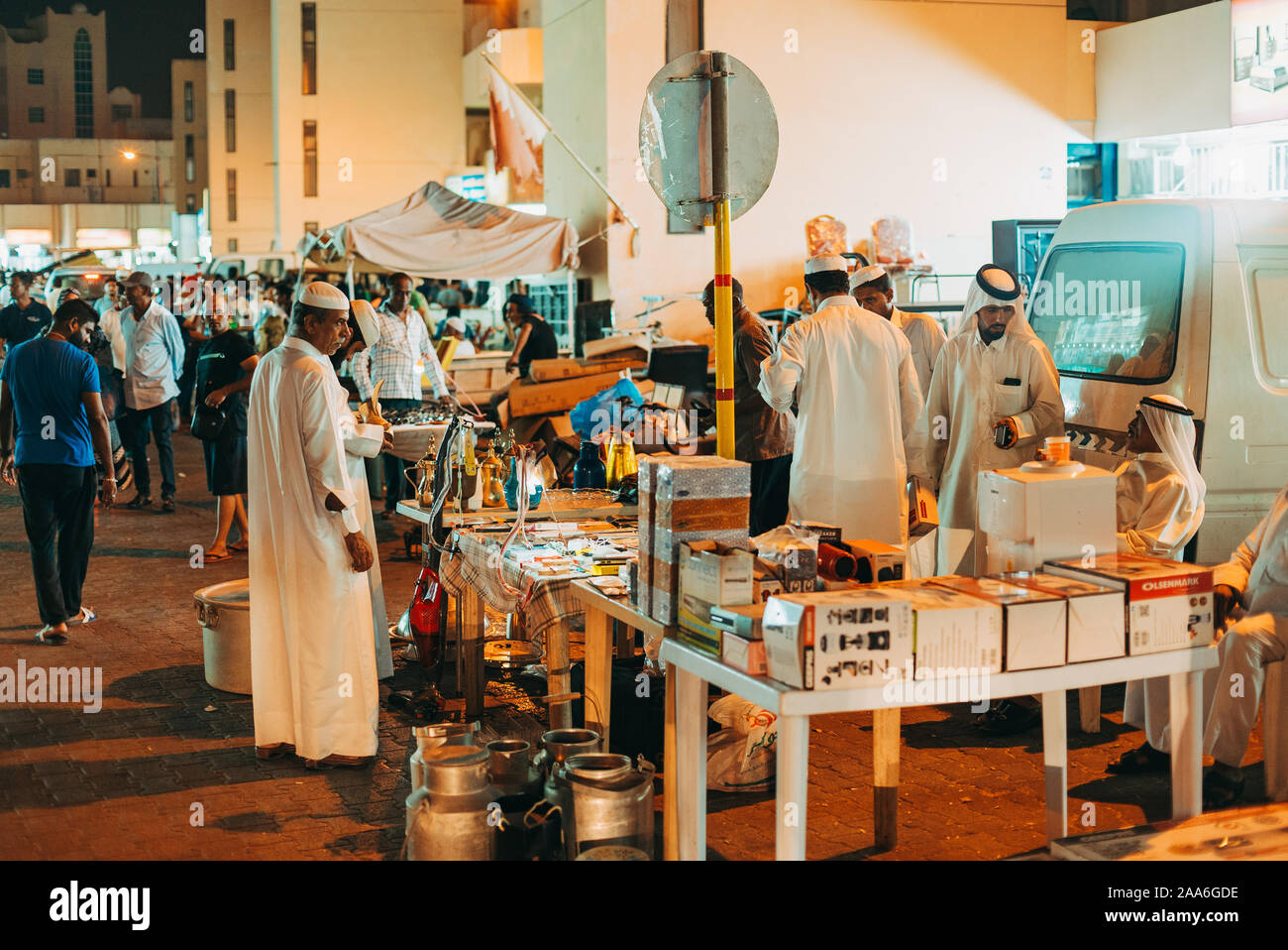 Men in traditional thobes sell and buy goods from street stalls in Souq ...