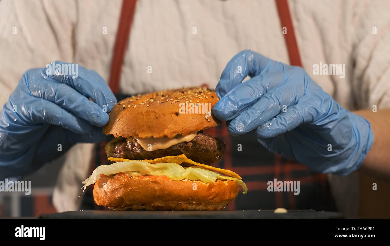 Close-up of a chef cooked a delicious hamburger. He pours the sauce and ...