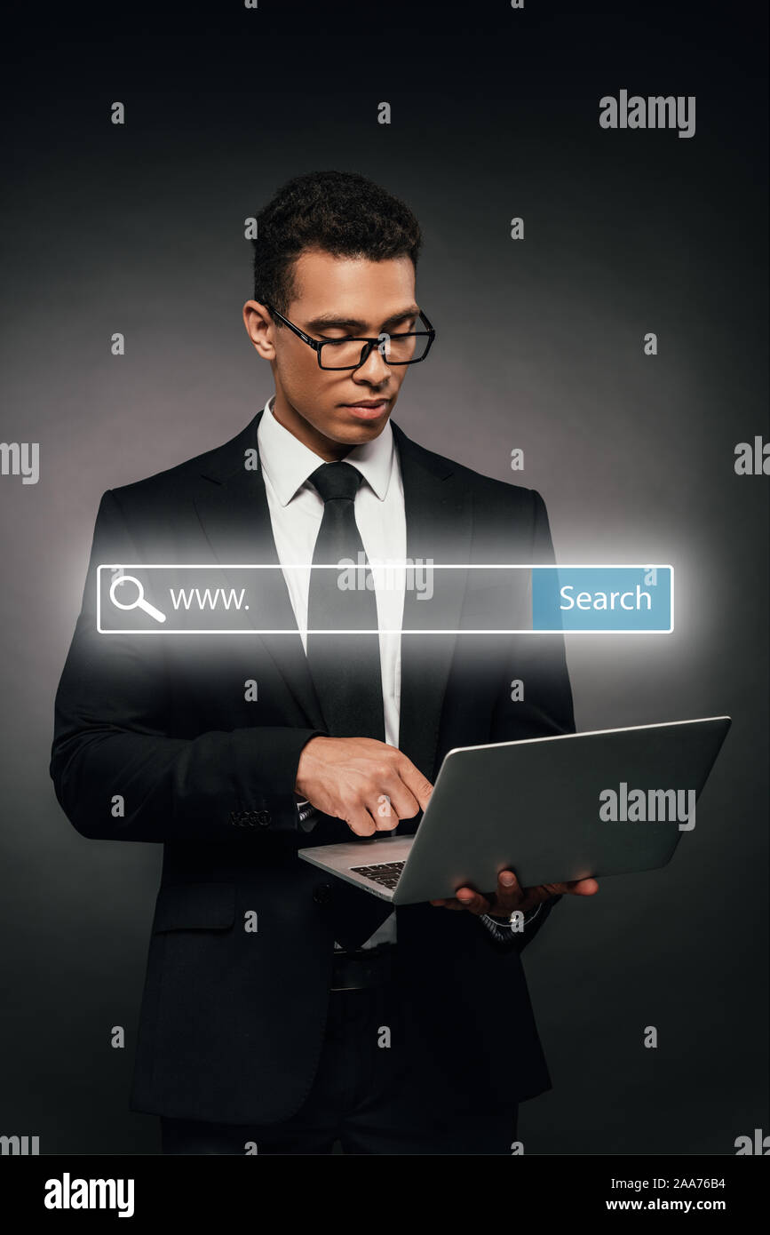 african american businessman using laptop on dark background with ...