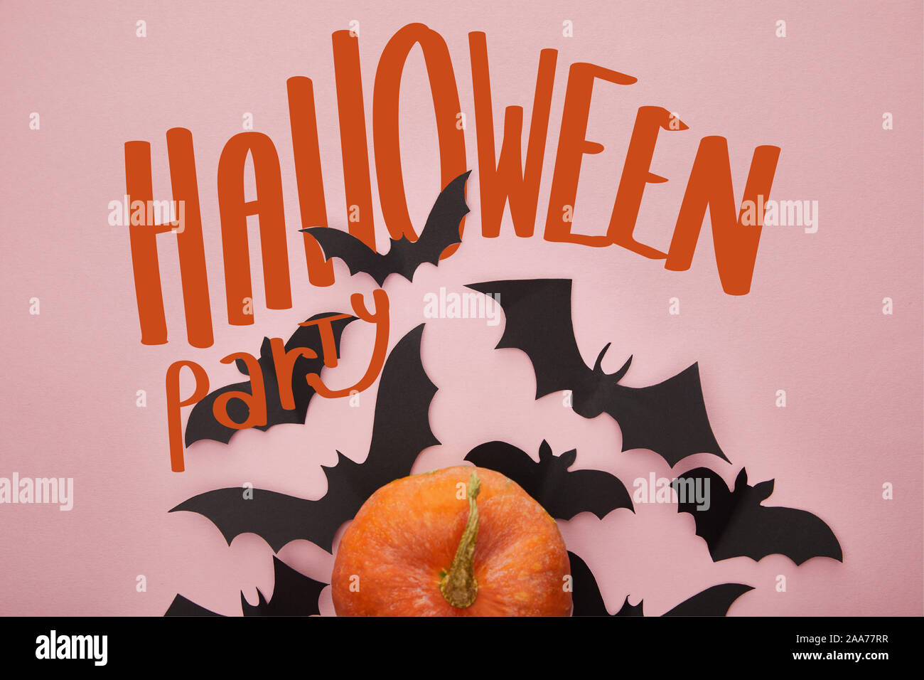 top view of pumpkin and paper bats on pink background with Halloween ...