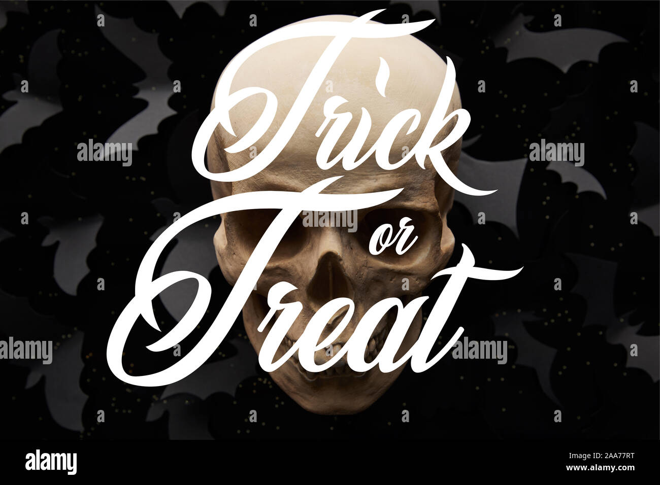 paper bats and skull on black background with trick or treat ...