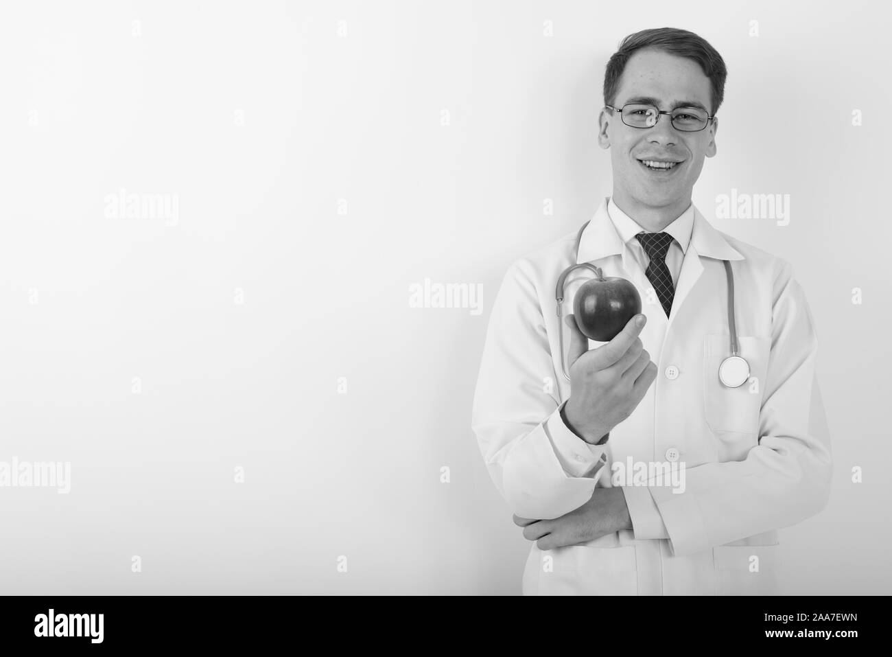Young handsome man doctor holding apple in black and white Stock Photo ...