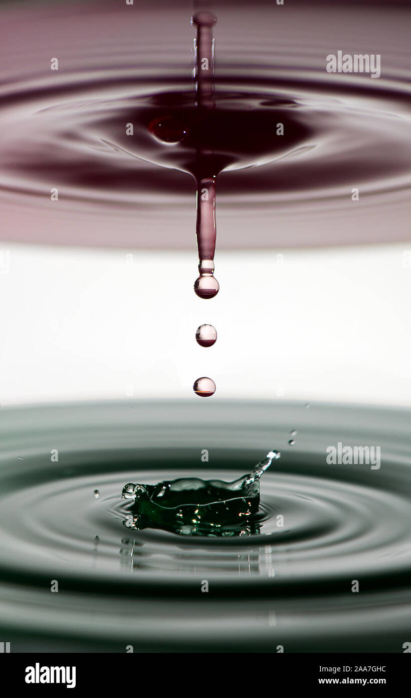 drops of a fluid dripping into another fluid against gravity rules ...