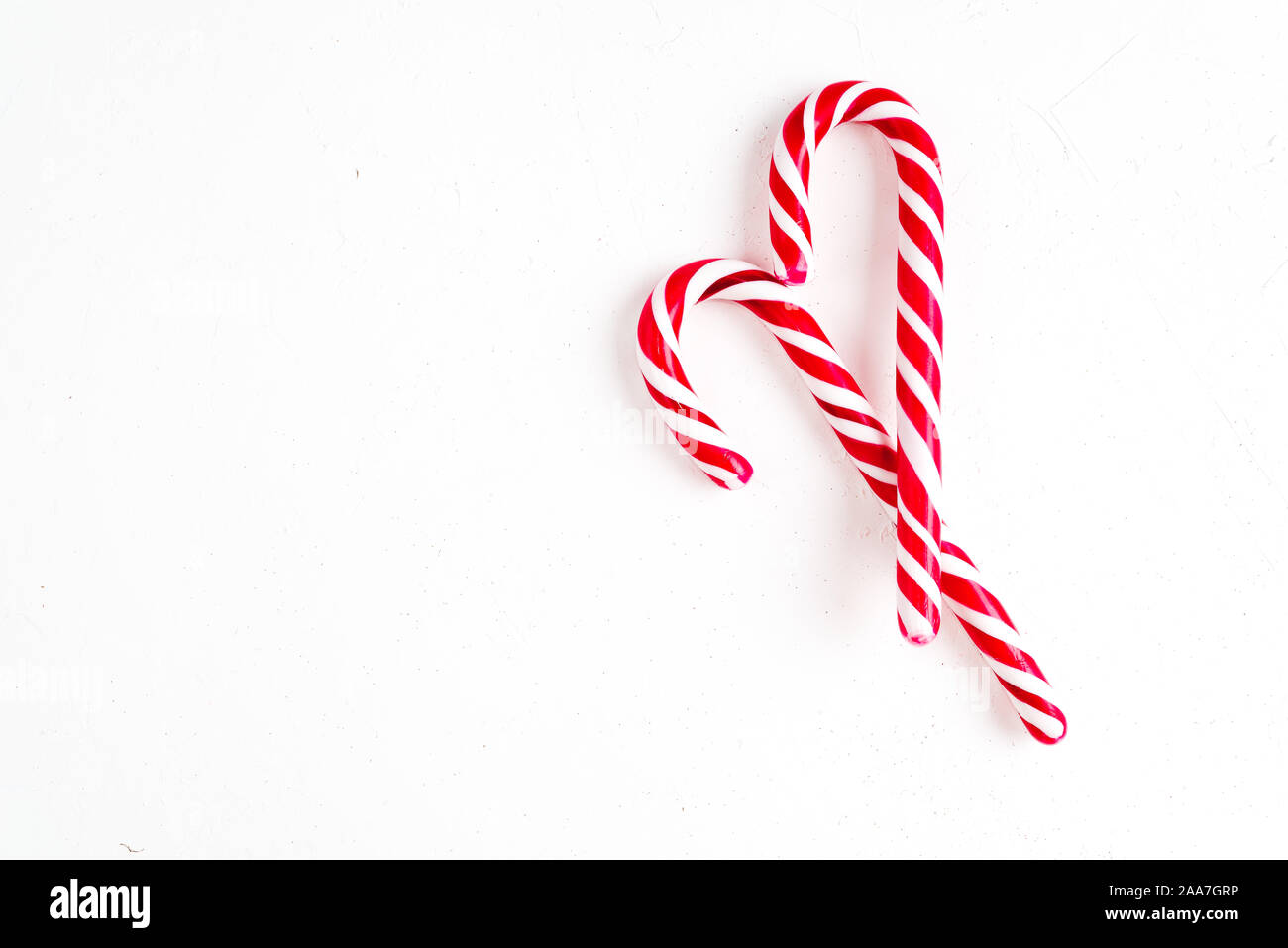 Candy canes on a white surface, top view Stock Photo - Alamy