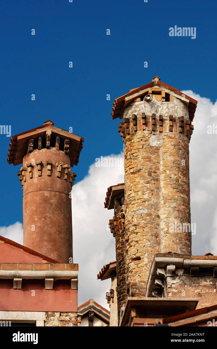 Venice, Ancient chimneys above the roofs with blue sky and clouds ...
