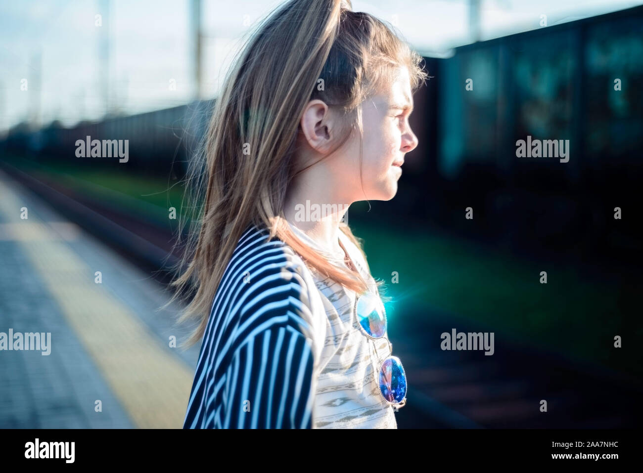 little teenage girl, with sunglasses, a backpack, is waiting for the ...