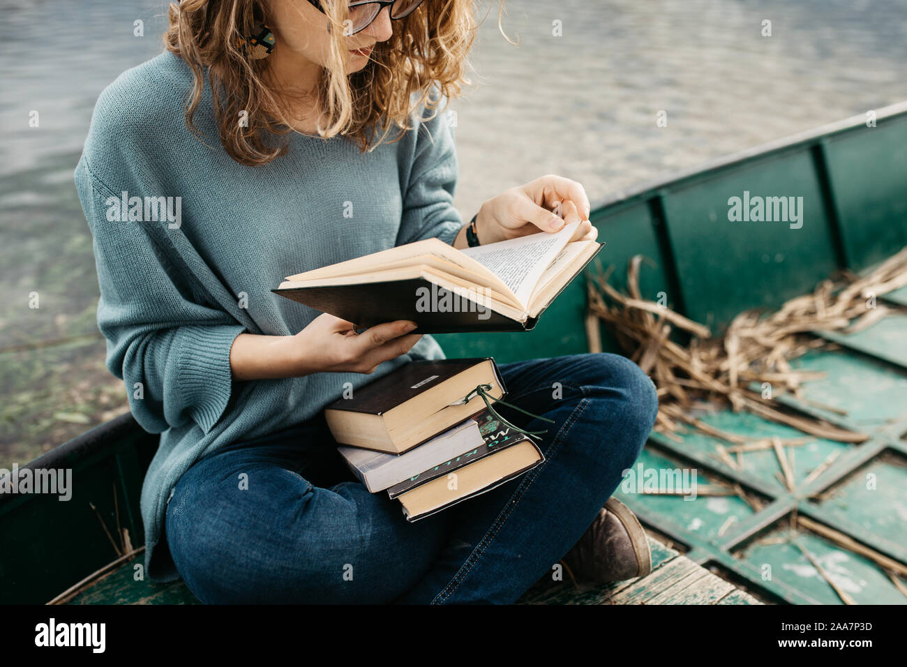 Portrait of young beautiful woman sitting on a boat and reading a book ...