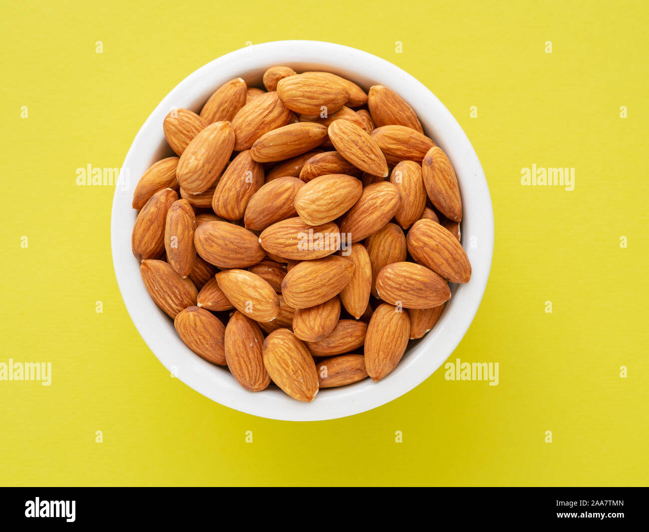 Top view of white cups, bowls with a handful of pecans, almonds on a ...