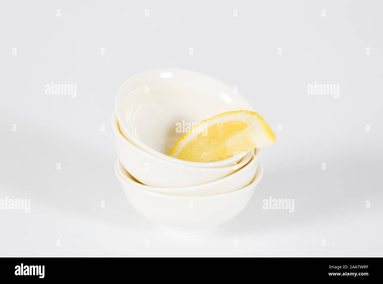 Small white bowls with a slice of lemon, studio shot with white ...