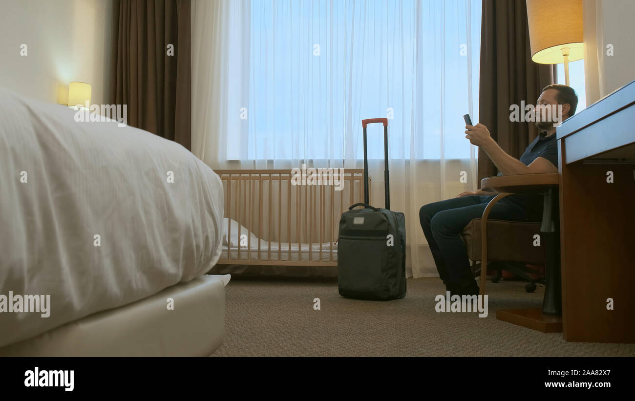 Family in the hotel room is waiting for a taxi. dad with a suitcase and ...