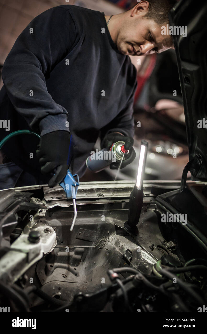 Car master mechanic repairer lubricates the screws with a machine parts ...