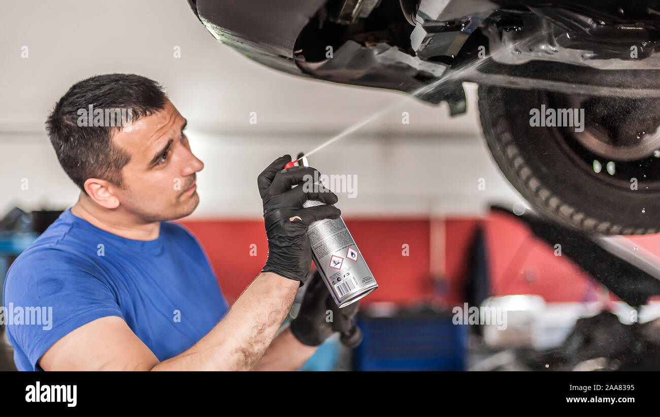 Car master mechanic repairer lubricates the screws with a machine parts ...