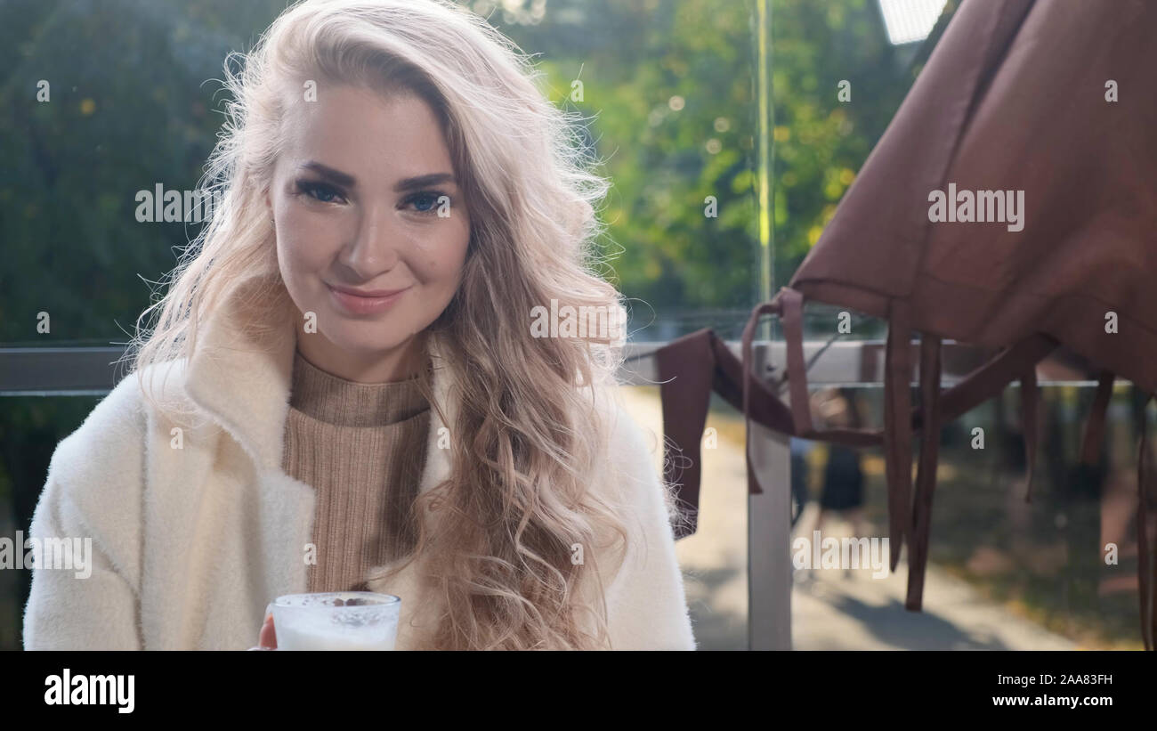 Beautiful lady is recording a video blog in an outdoor cafe. Young ...