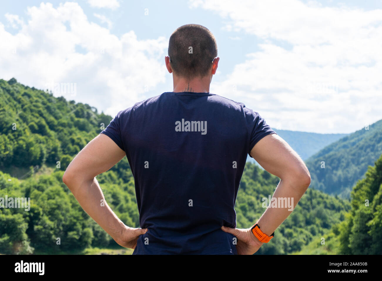 Adult man standing back to camera and looking on mountains Stock Photo ...