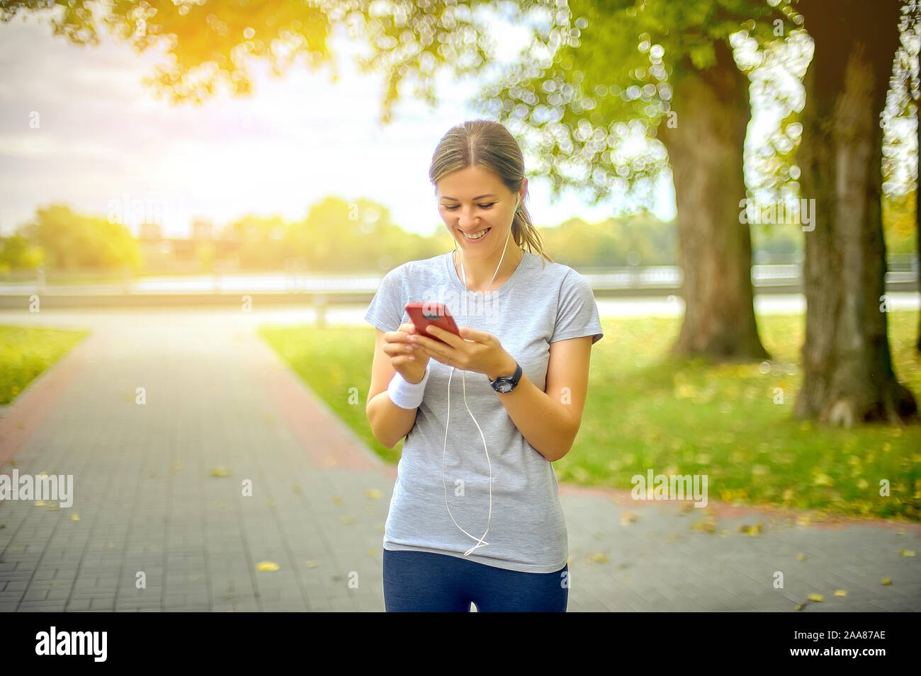 Girl athlete jogging in the evening park. Resting and talking on social ...