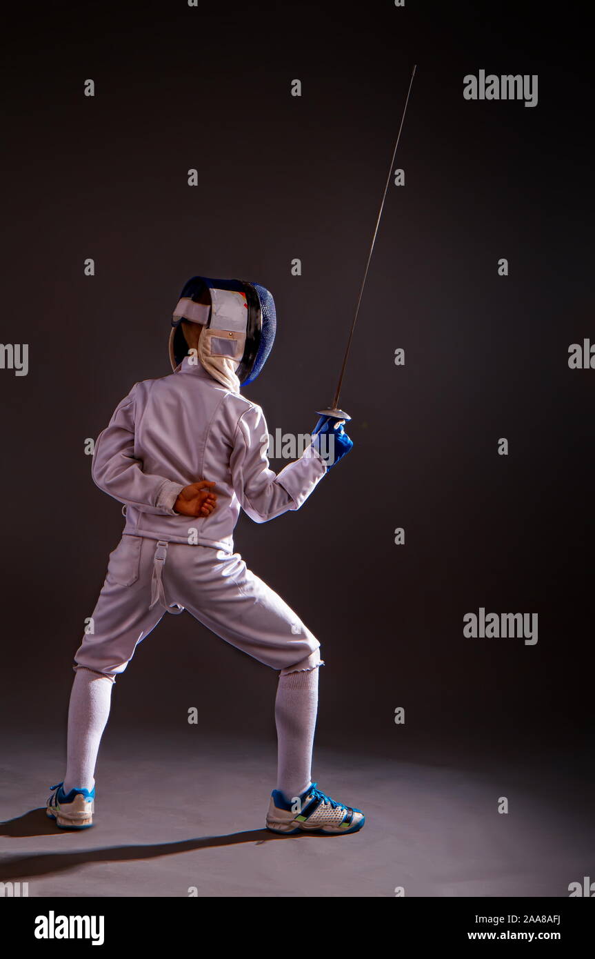 Little boy in a white protective suit fencing mask and with a rapier ...