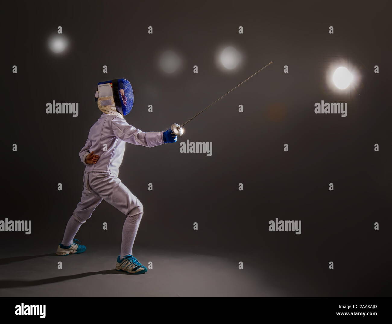 Little boy in a white protective suit fencing mask and with a rapier ...