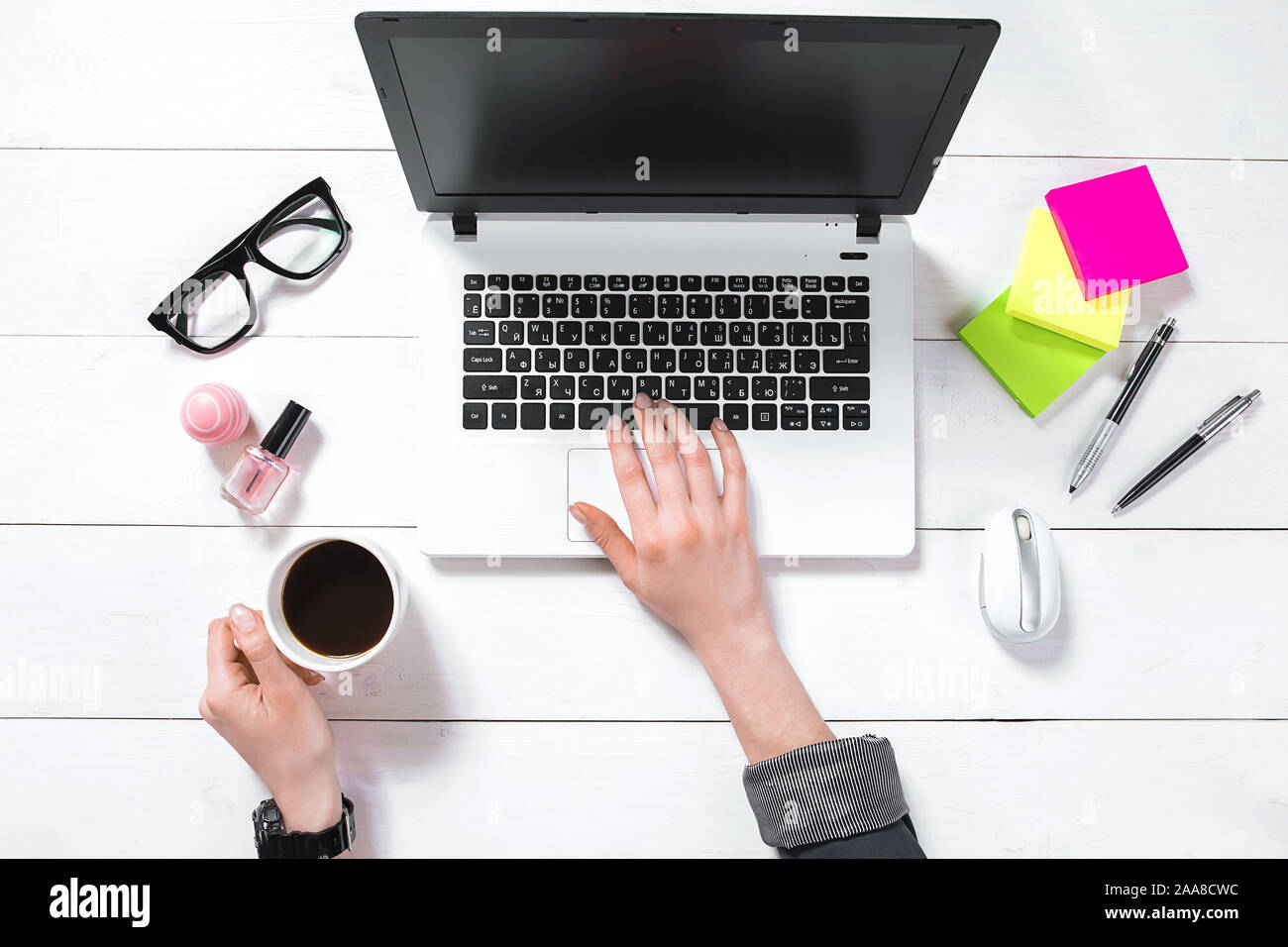 Top view of woman's hands typing on laptop keypad placed on white ...