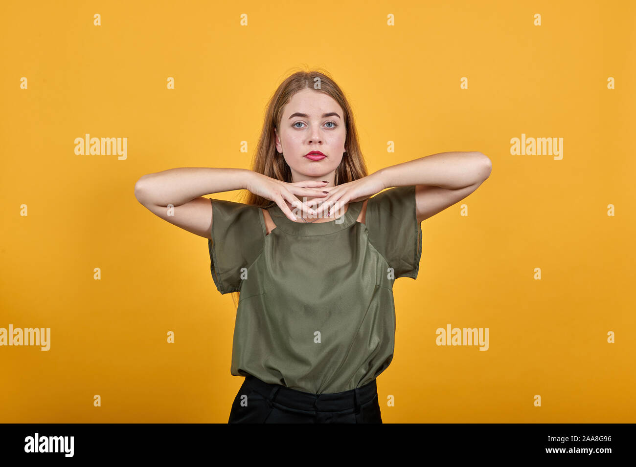 Portrait of cute smiling young woman in nice shirt putting hand under ...