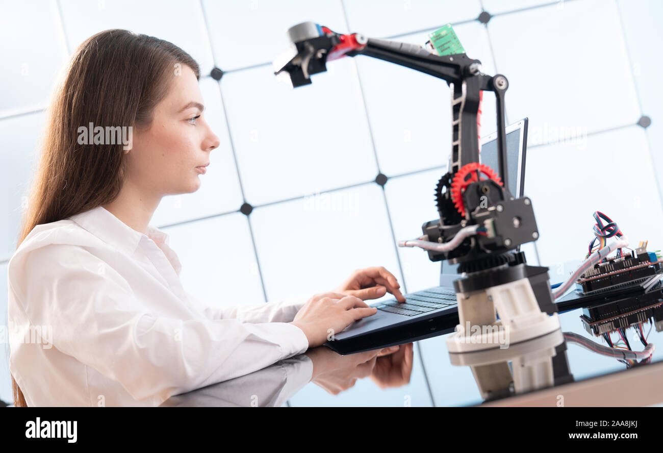 A young woman writes an algorithm for the robot arm. Science Research ...