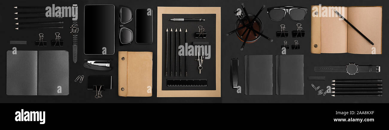Office desktop with various black objects on black background. Top view ...