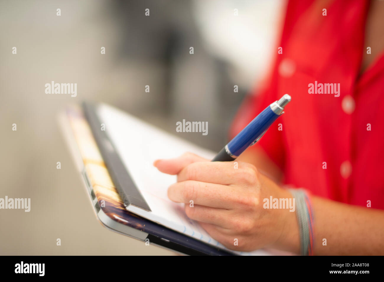 Left handed woman taking notes with a pen and pad of paper Stock Photo ...