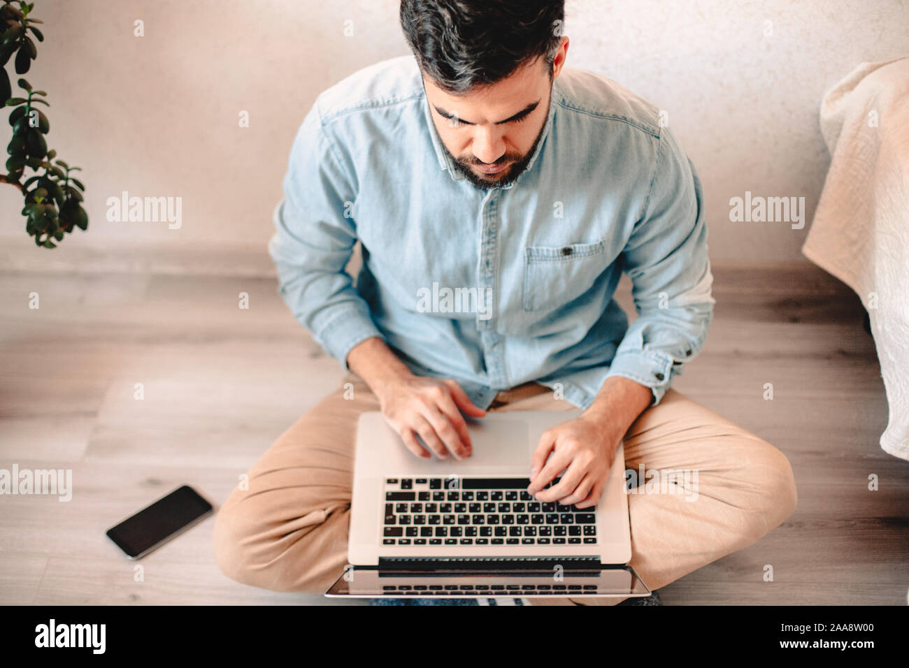 Young man using laptop computer while sitting on floor at home Stock ...
