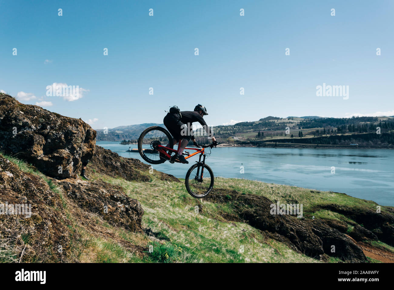 A biker jumps off a rock on a trail overlooking the Columbia Gorge ...