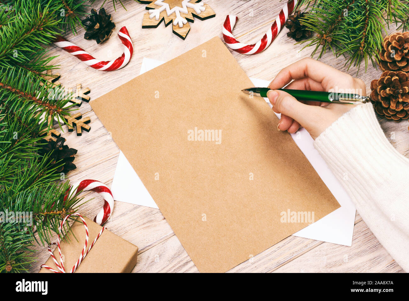Famale hand writing a Christmas letter on wooden background. Toned ...