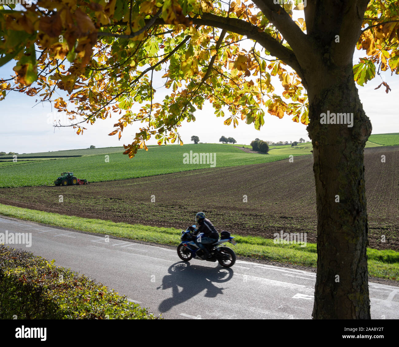 motorcycle on country road and tractor with harrow on field in dutch ...
